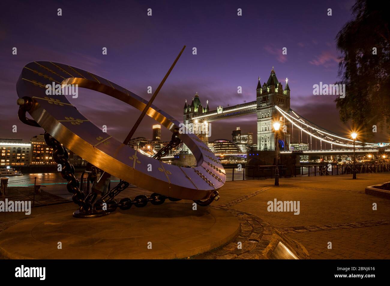 Tower Bridge with the sundial statue at St. Katherines Dock at night ...