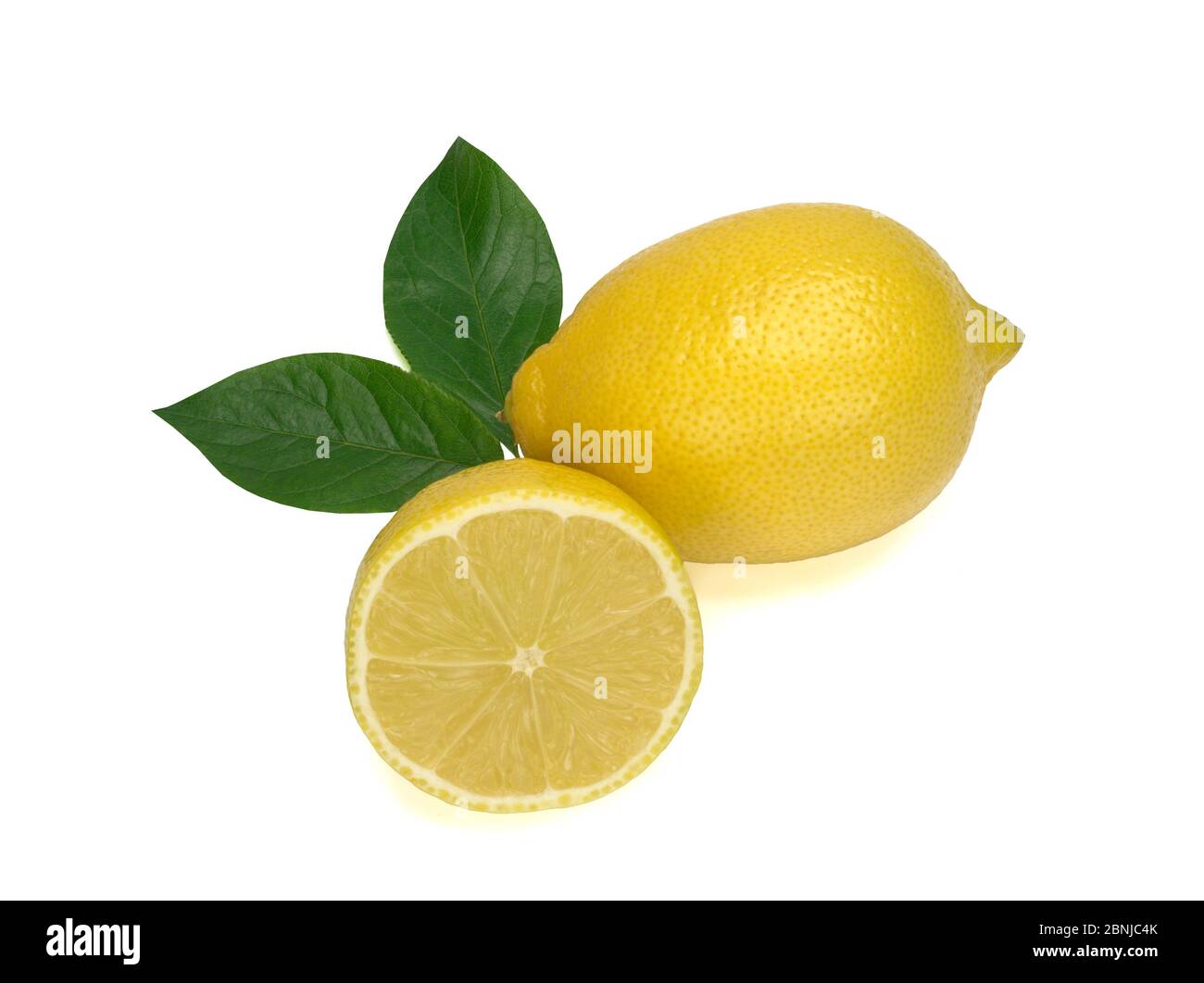 One whole yellow lemon and a half of lemon with green leaves isolated ...