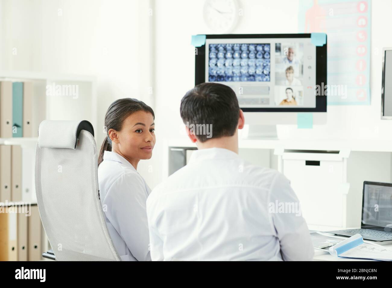 Two doctors talking to each other while sitting at the table and ...