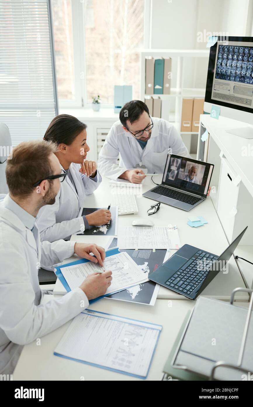 Group of doctors sitting at the table and talking to their colleague ...