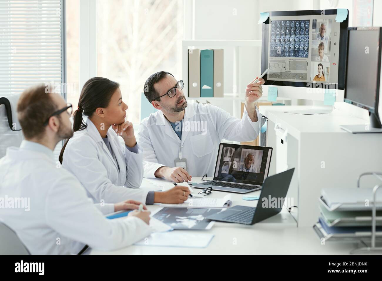 Doctor pointing at computer monitor and discussing x-ray images with ...