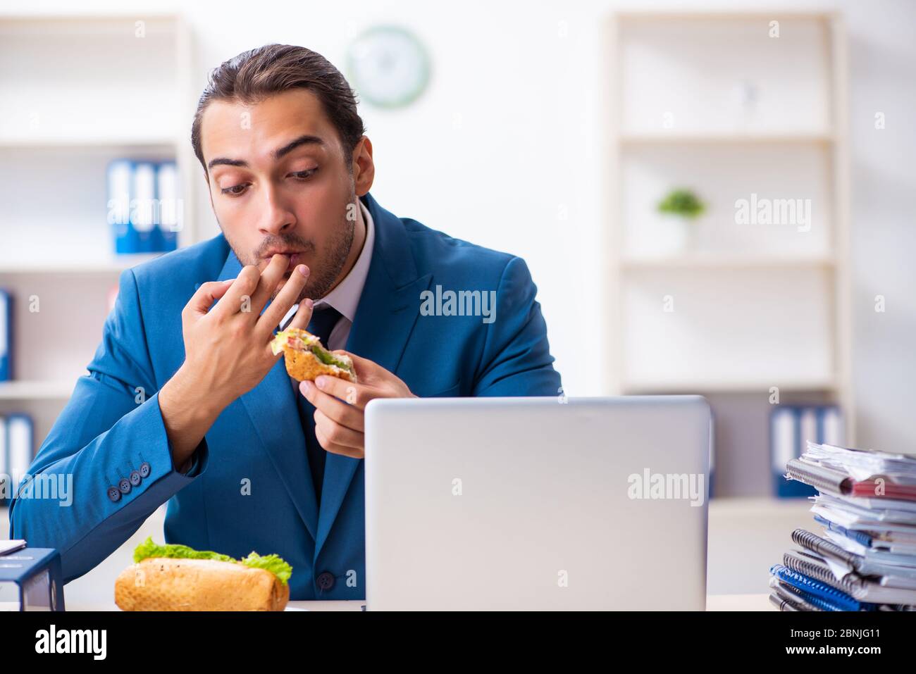 Young employee having breakfast at workplace Stock Photo - Alamy