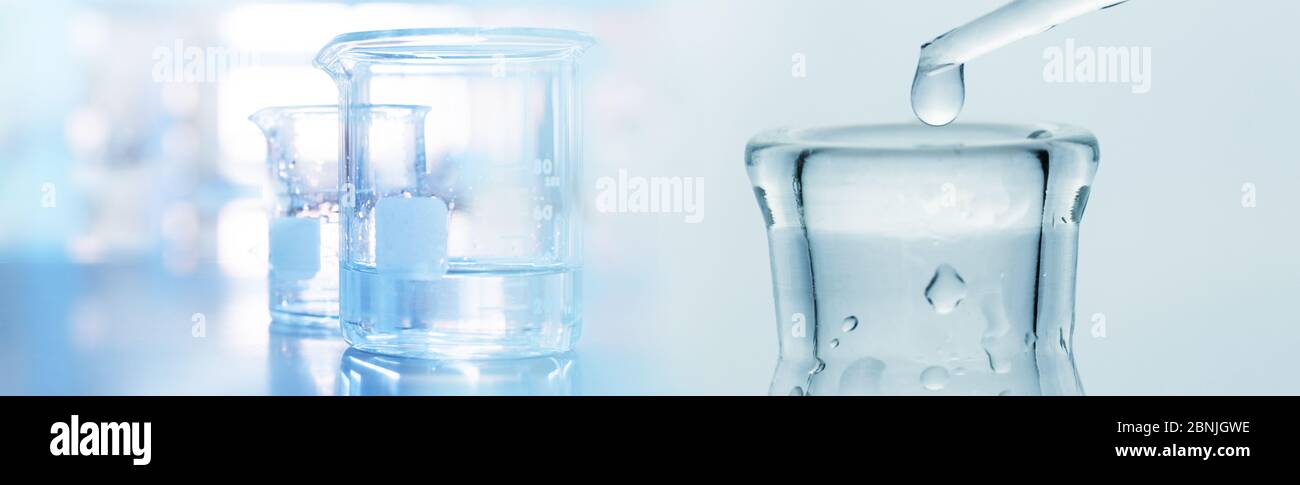 water drop into research glass flask and beaker in soft blue light ...
