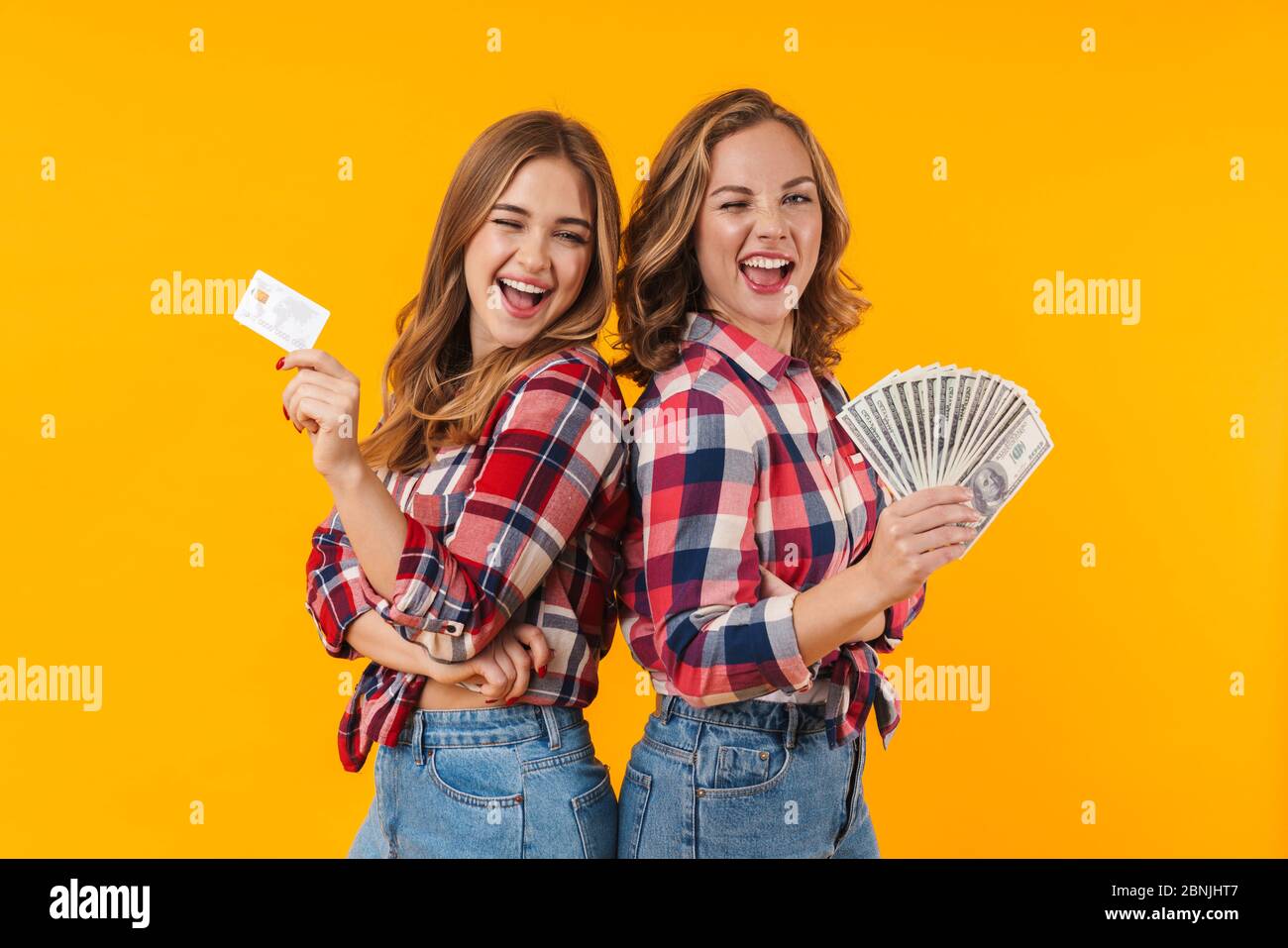 Image of two young beautiful girls wearing plaid shirts holding dollar ...