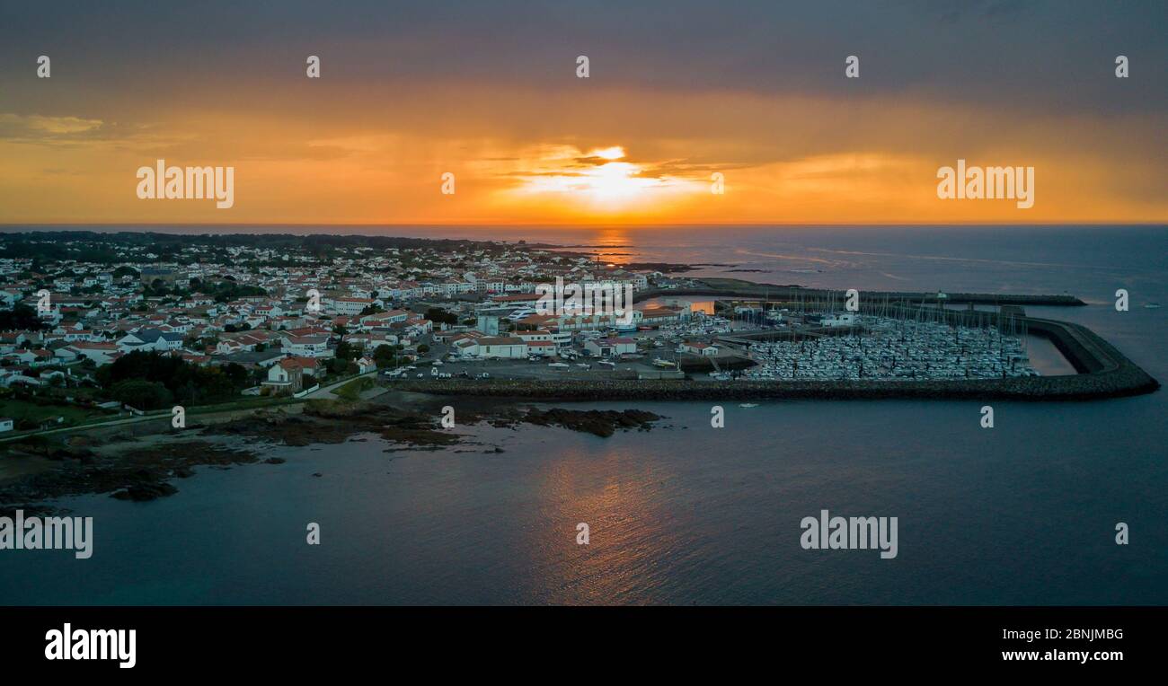 Warm and cloudy sunset faces the harbor of the wonderful Yeu island in ...