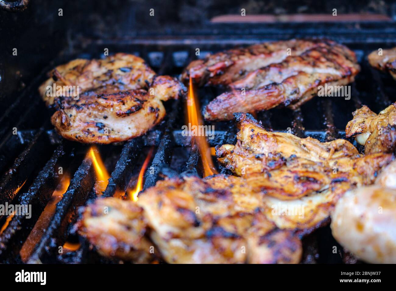 Meat being flame grilled on a barbecue, BBQ flame grill Stock Photo - Alamy