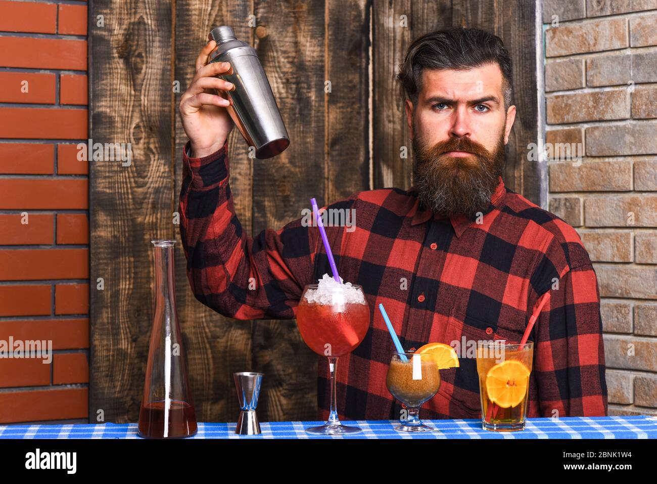 Barman and cocktails concept. Man in checkered shirt on wooden texture ...