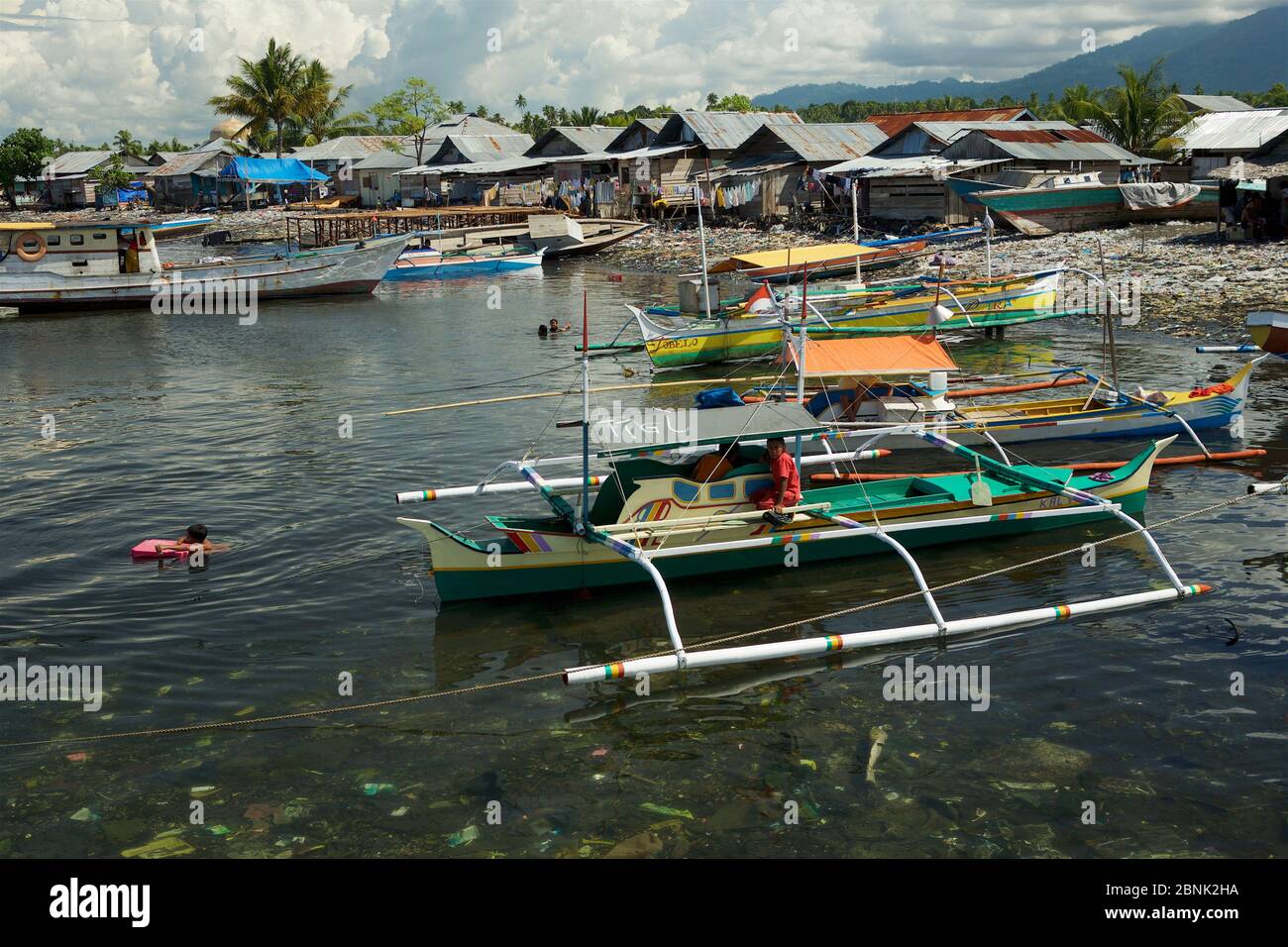 Litter strewn beach with houses and outrigger boats at Tobelo Town ...