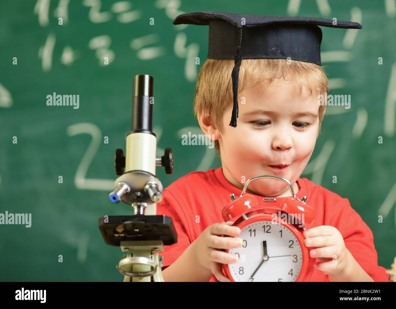 School break concept. Child on excited face looks at alarm clock. Pupil ...