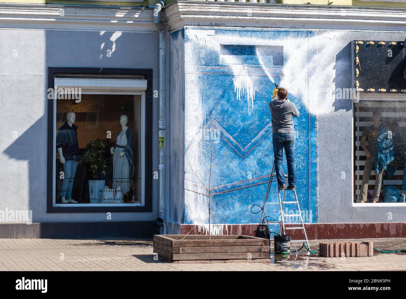 A man washes the facade and shop windows. Modern equipment and cleaning ...