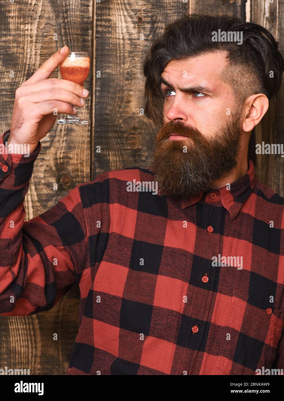 Suspicious drink concept. Barman with beard and serious face looks at ...