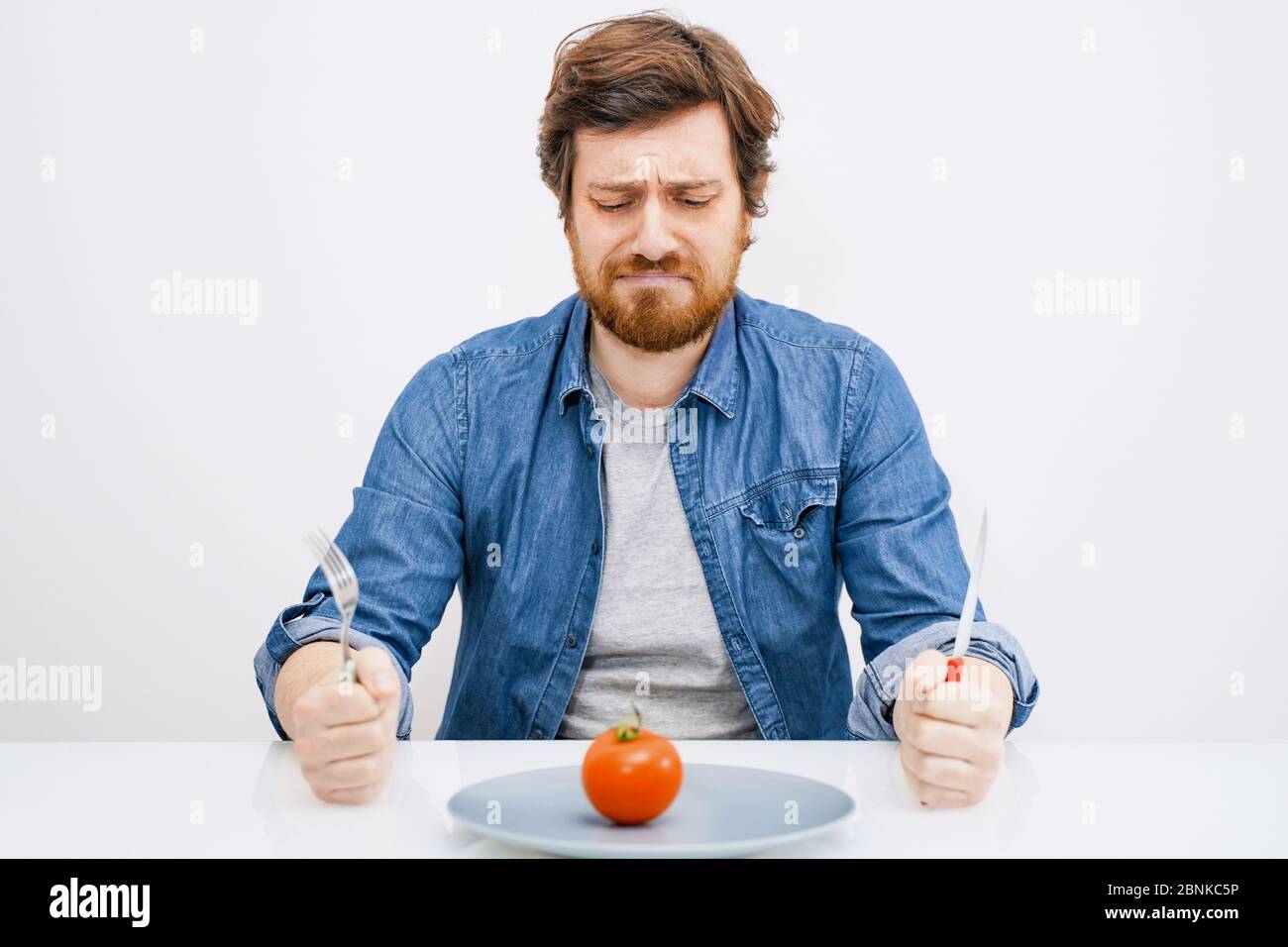 Sad hungry man eating vegetables isolated on white background Stock ...