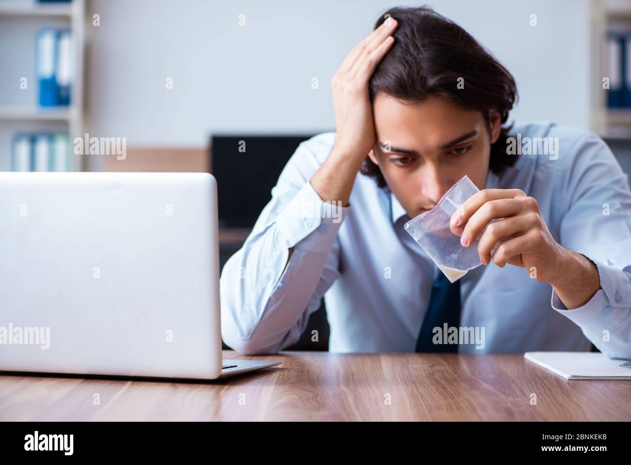 The young man having problems with narcotics at workplace Stock Photo ...