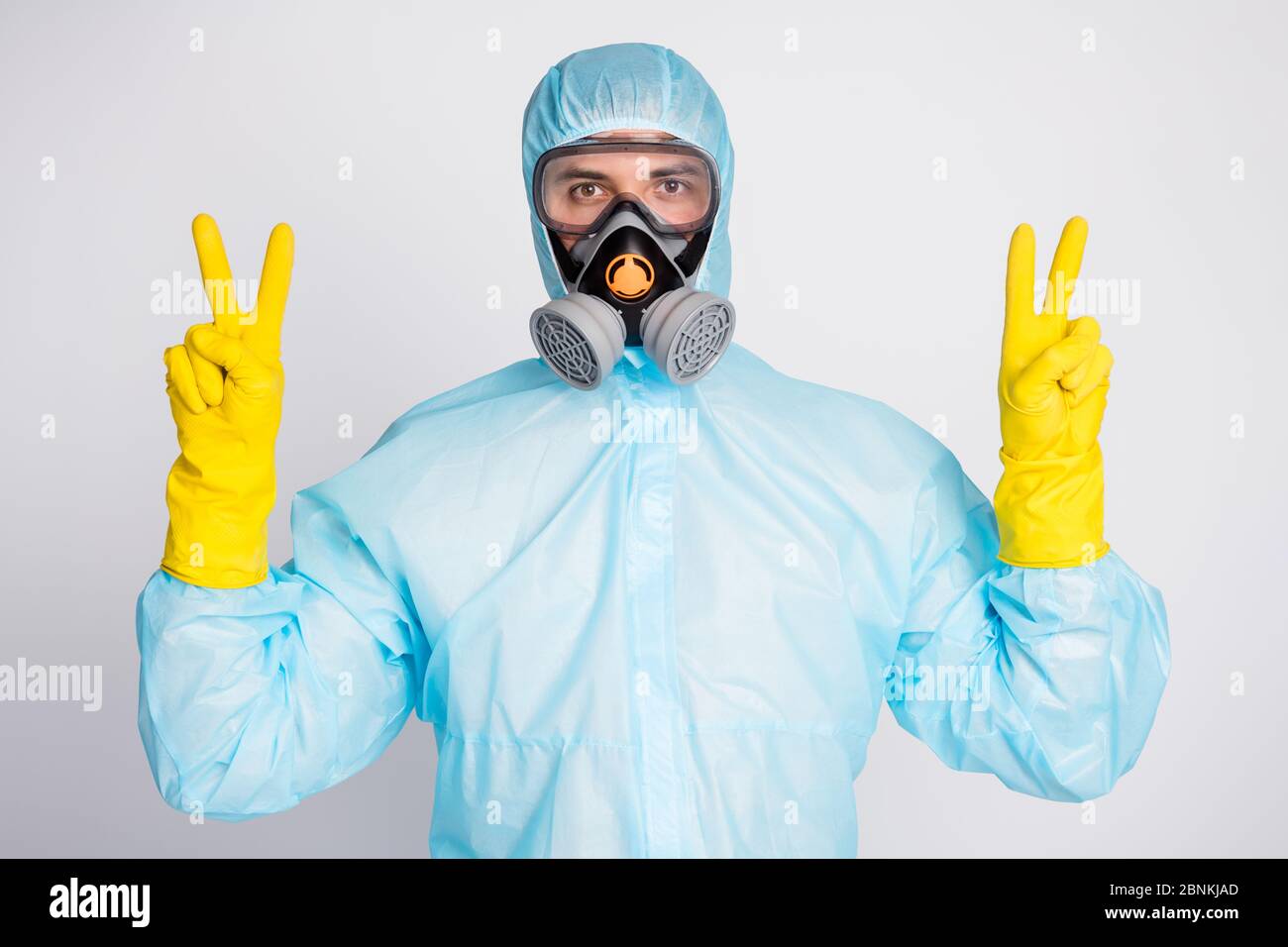 Portrait of medical man worker make v-sign wear white biohazard uniform ...