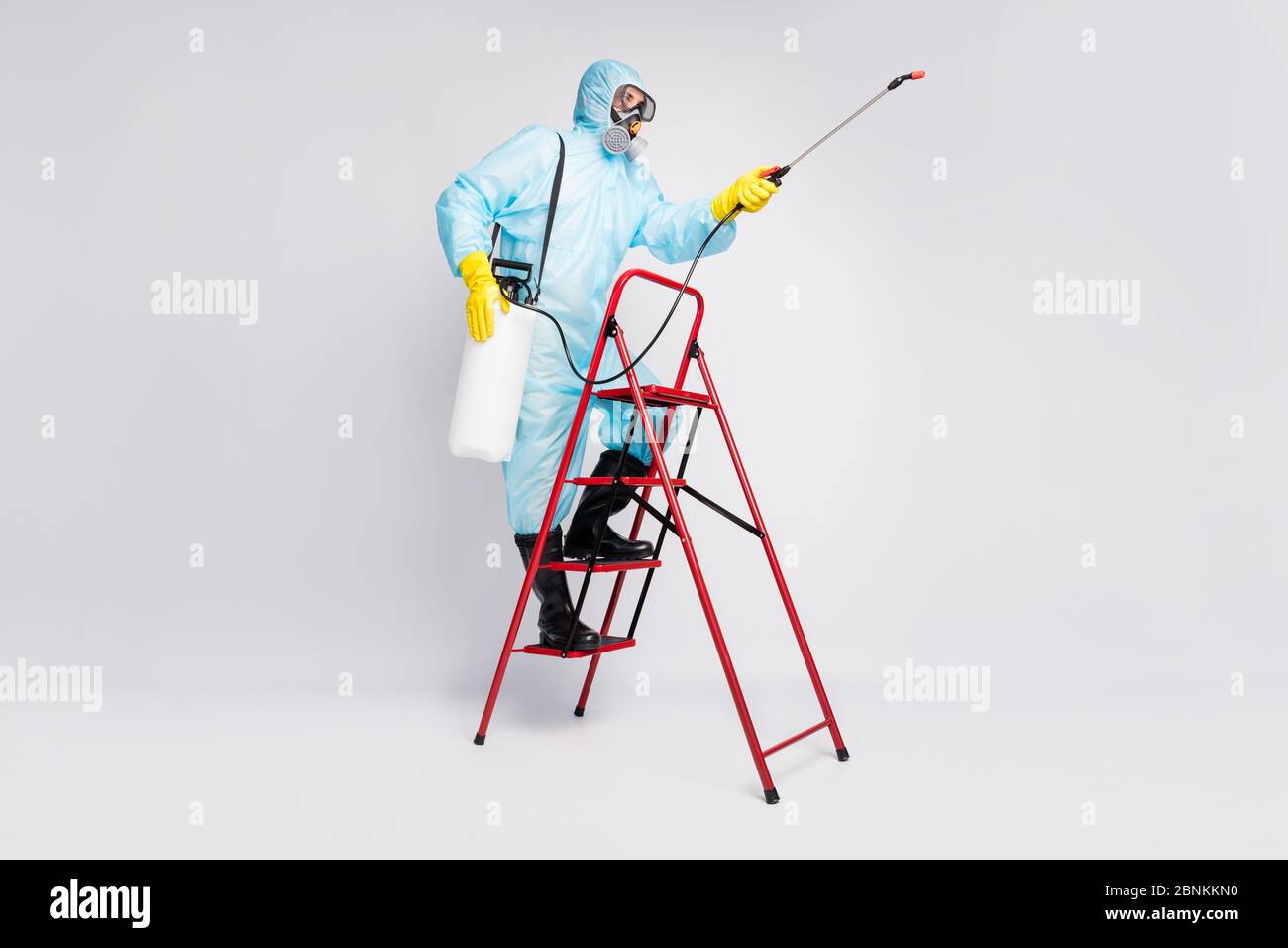 Full length profile side photo of man climb ladder use spray disinfect ...
