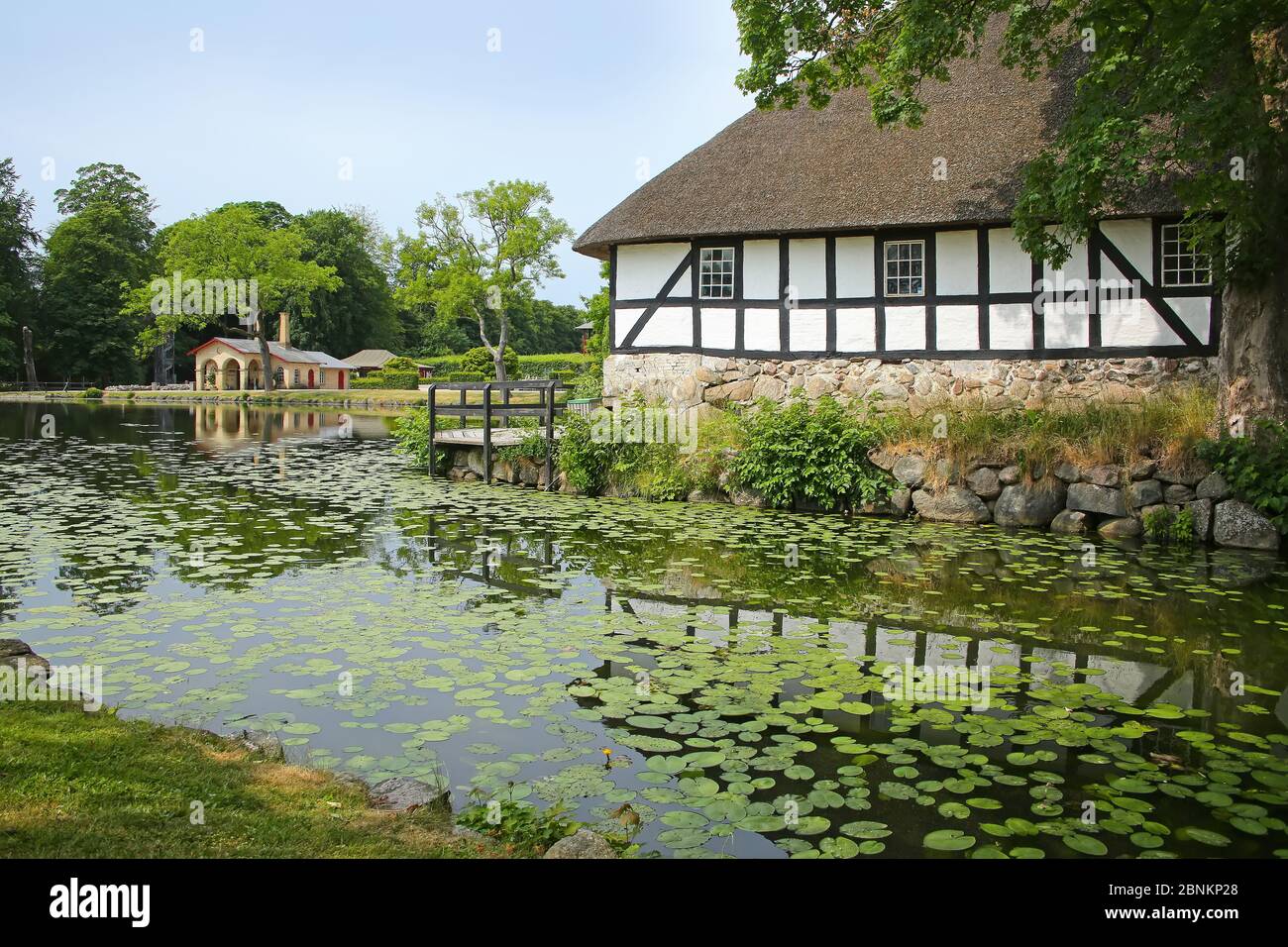 Traditional half timber building on edge of a beautiful lake with lily ...