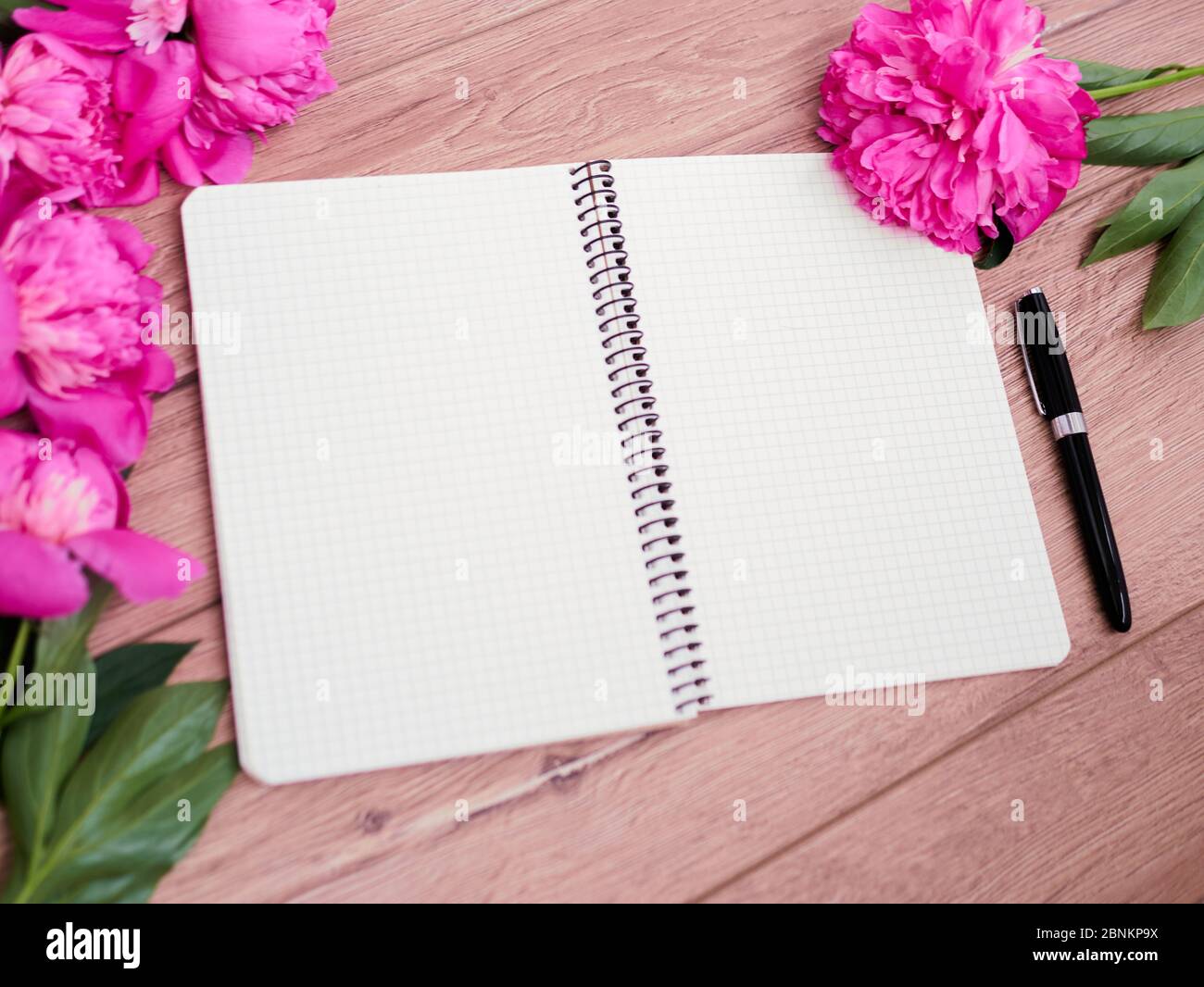 Pink peony flowers,empty notebook on wooden table top view in flat lay ...