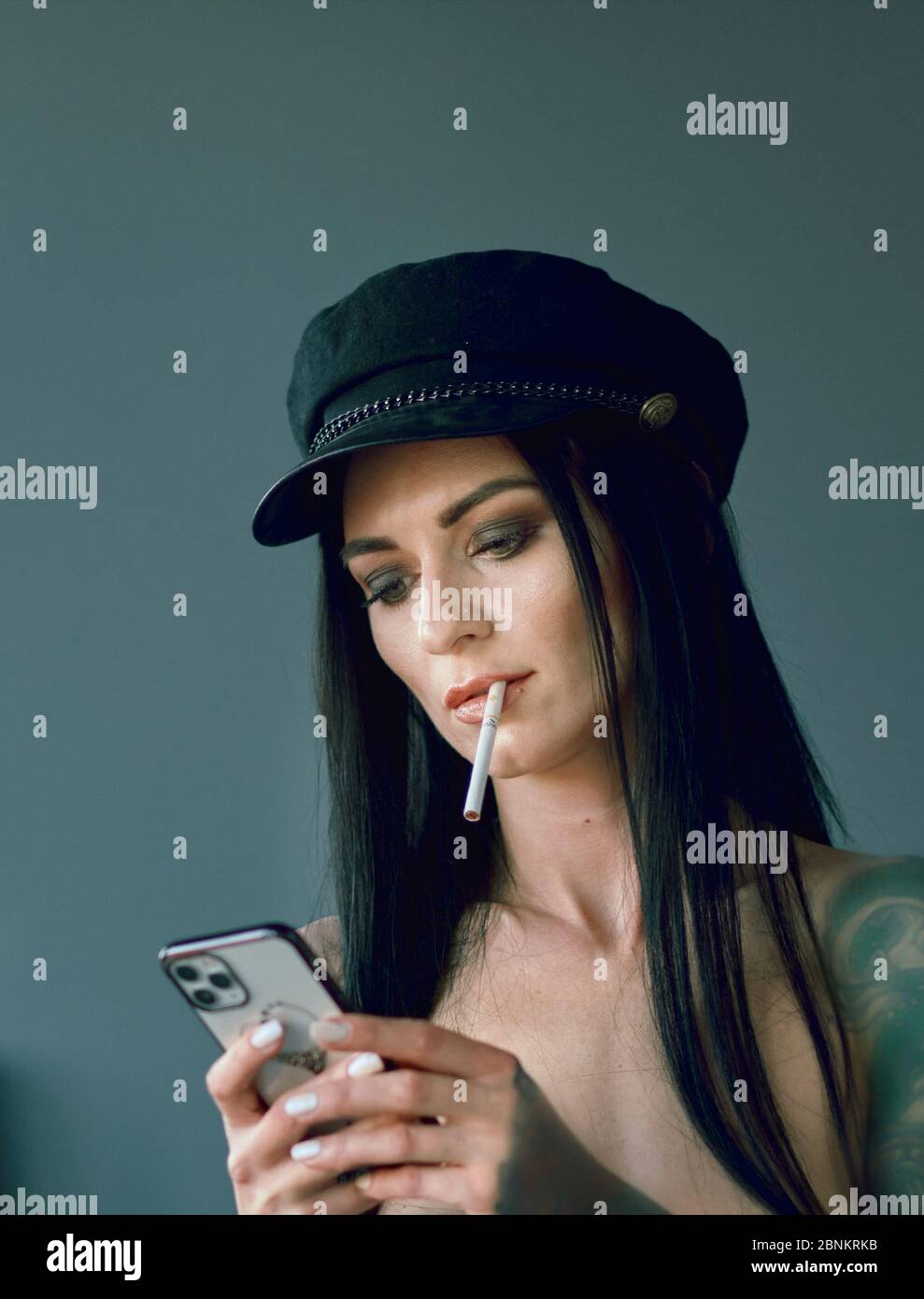 Beautiful young woman in black hat with long dark hair smoking ...