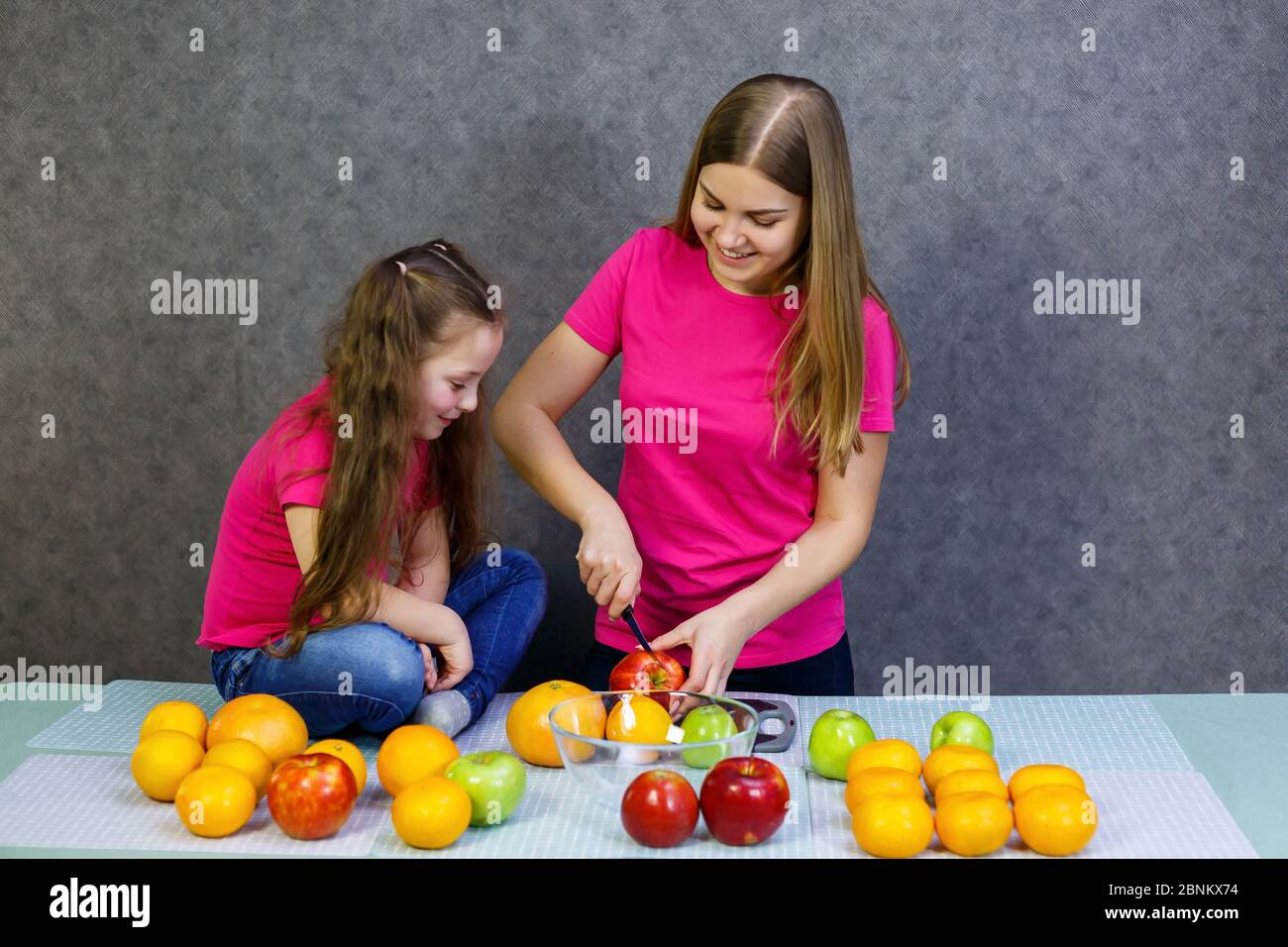 daughter and mom cut a fruit salad consisting of apple orange and ...