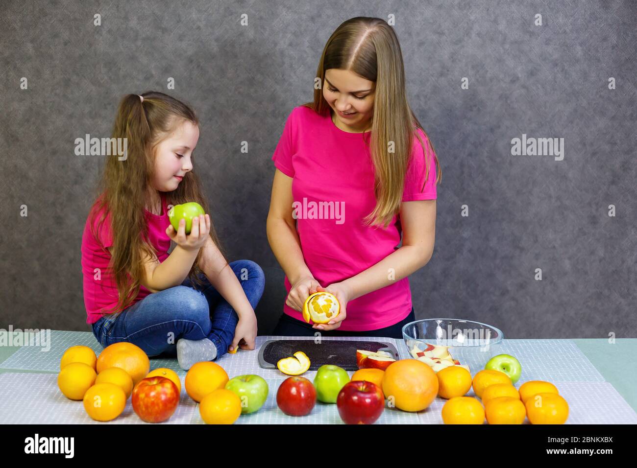 daughter and mom cut a fruit salad consisting of apple orange and ...