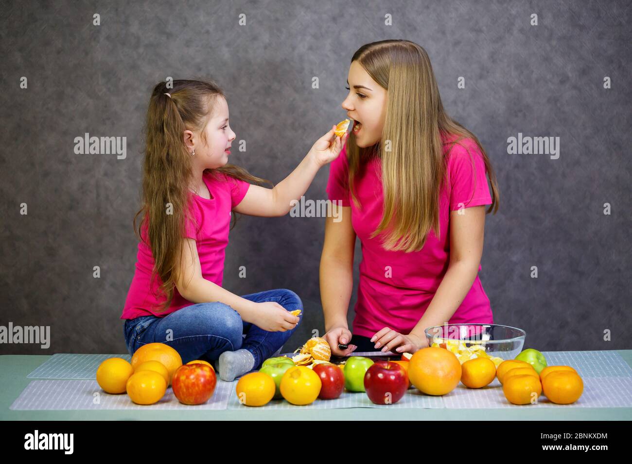 daughter and mom cut a fruit salad consisting of apple orange and ...