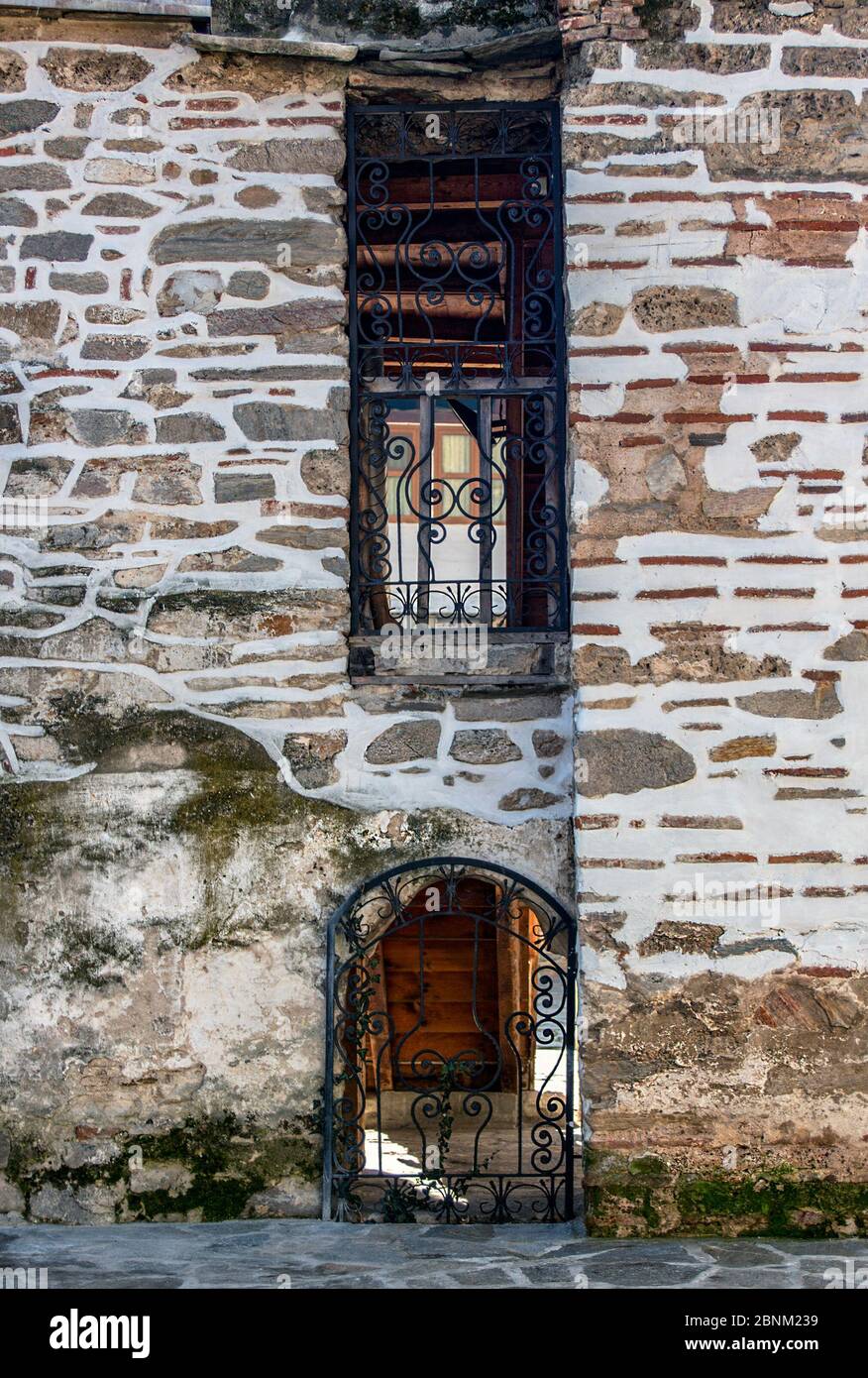 Medieval monastery wall with a door and a window with wrought iron ...