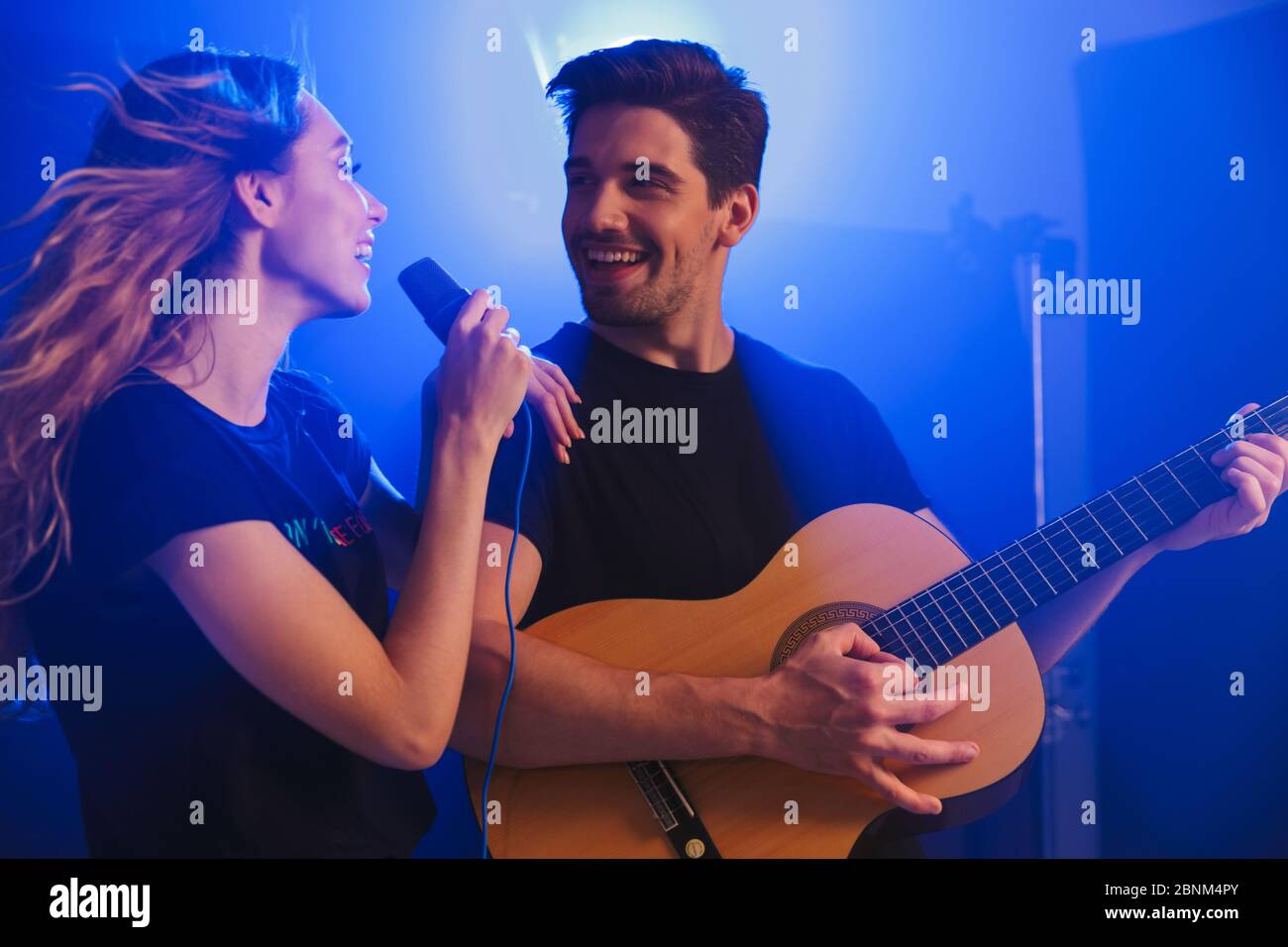 Photo of cheerful loving couple musicians group duet on scene in night ...