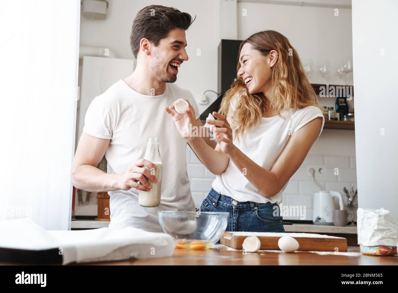 Image of excited young couple rejoicing while cooking breakfast ...