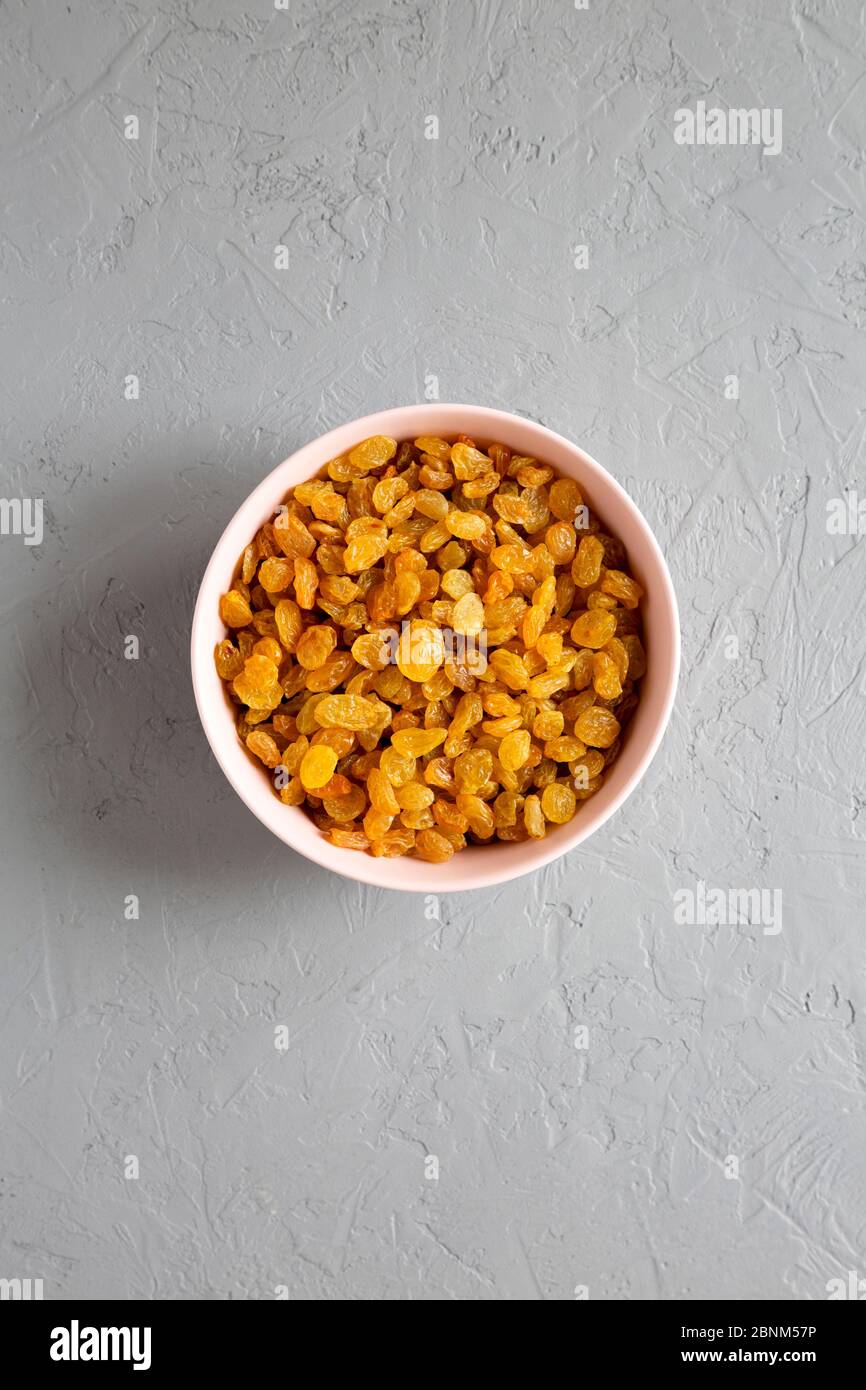 Golden Raisins in a Pink Bowl on a gray surface, top view. Flat lay ...