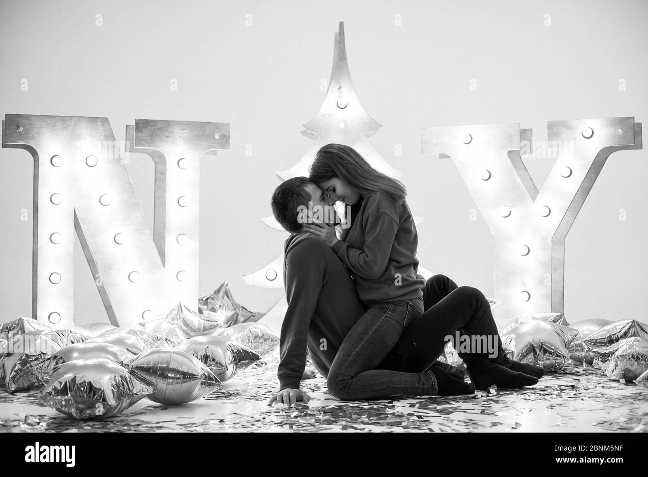 A romantic moment. A couple in red sweaters lies on the floor hugging ...