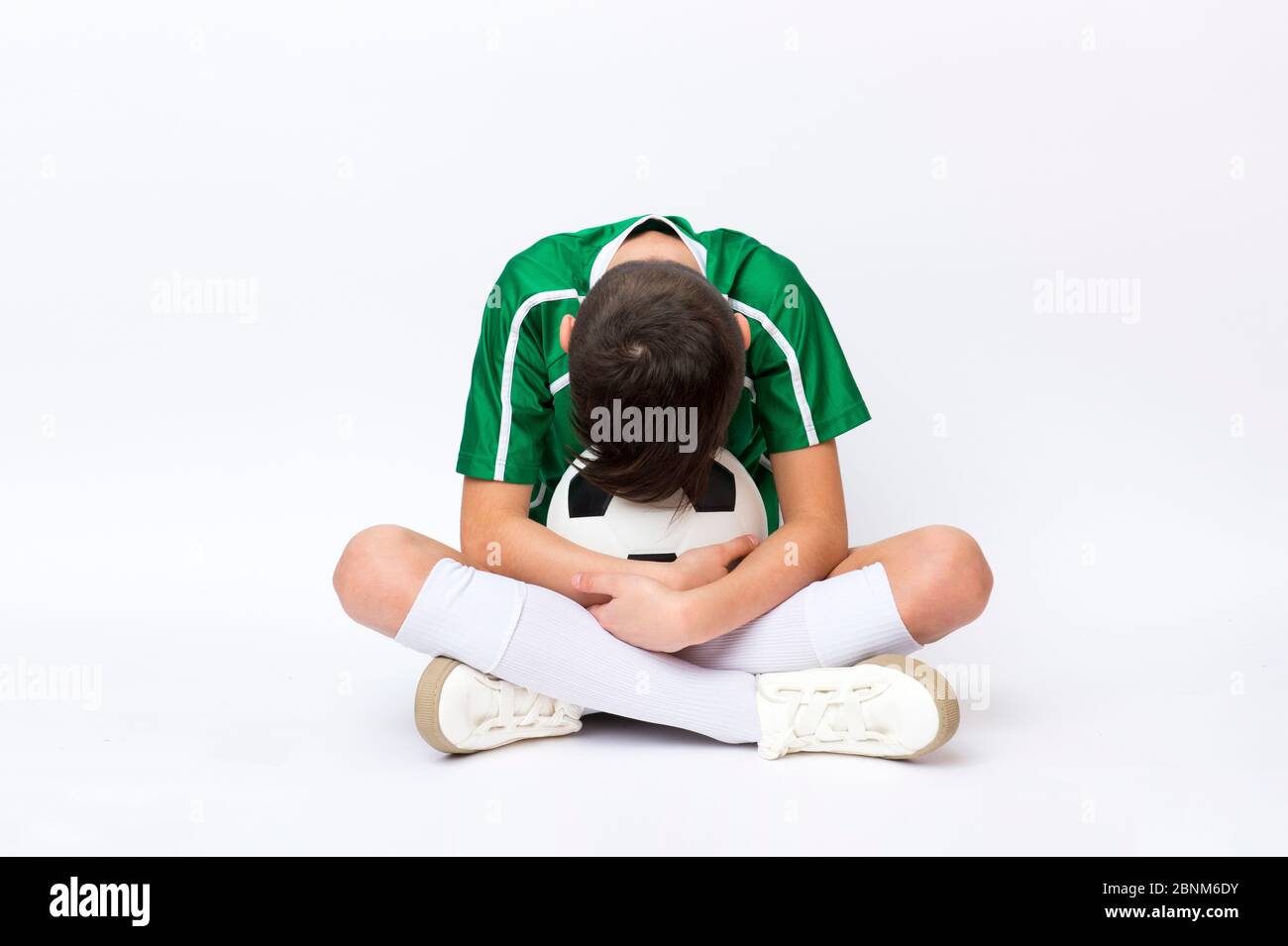 Sad kid with soccer ball over white background. Kid activities.Training ...
