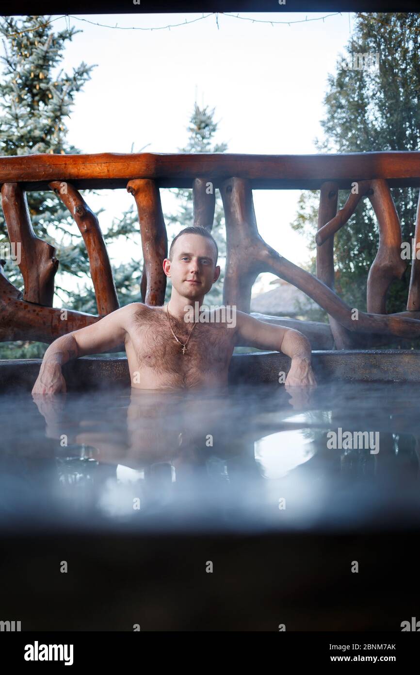 Young man in the pool with hot water on the terrace, spa body ...