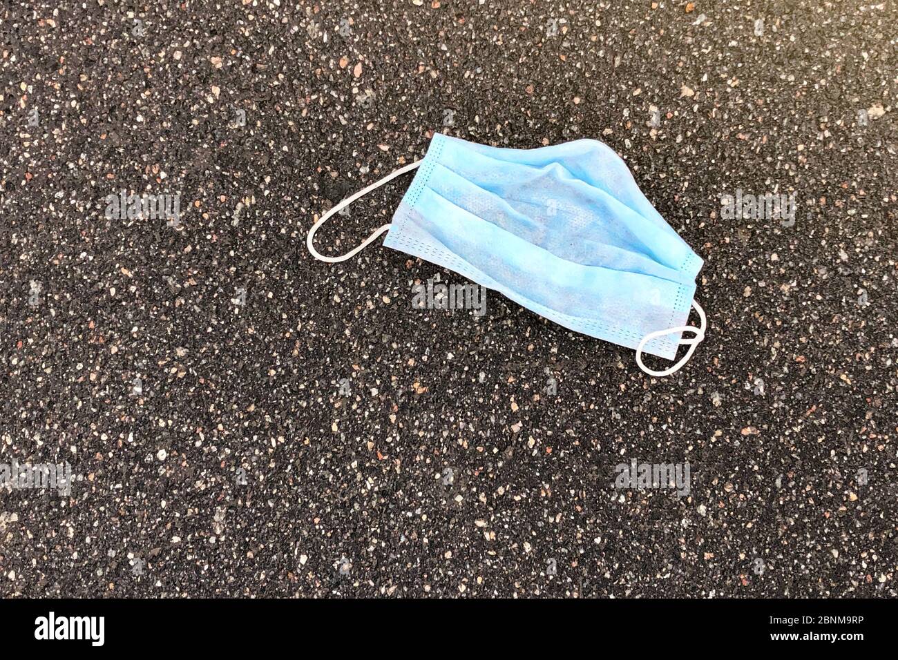 Medical hygiene mask used lies on asphalt in a city during a pandemic ...