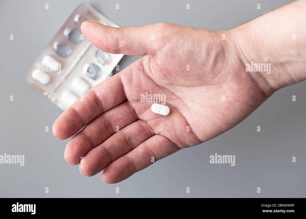 Close-up male palm with a tablet. Man holding a white pill in his hand ...