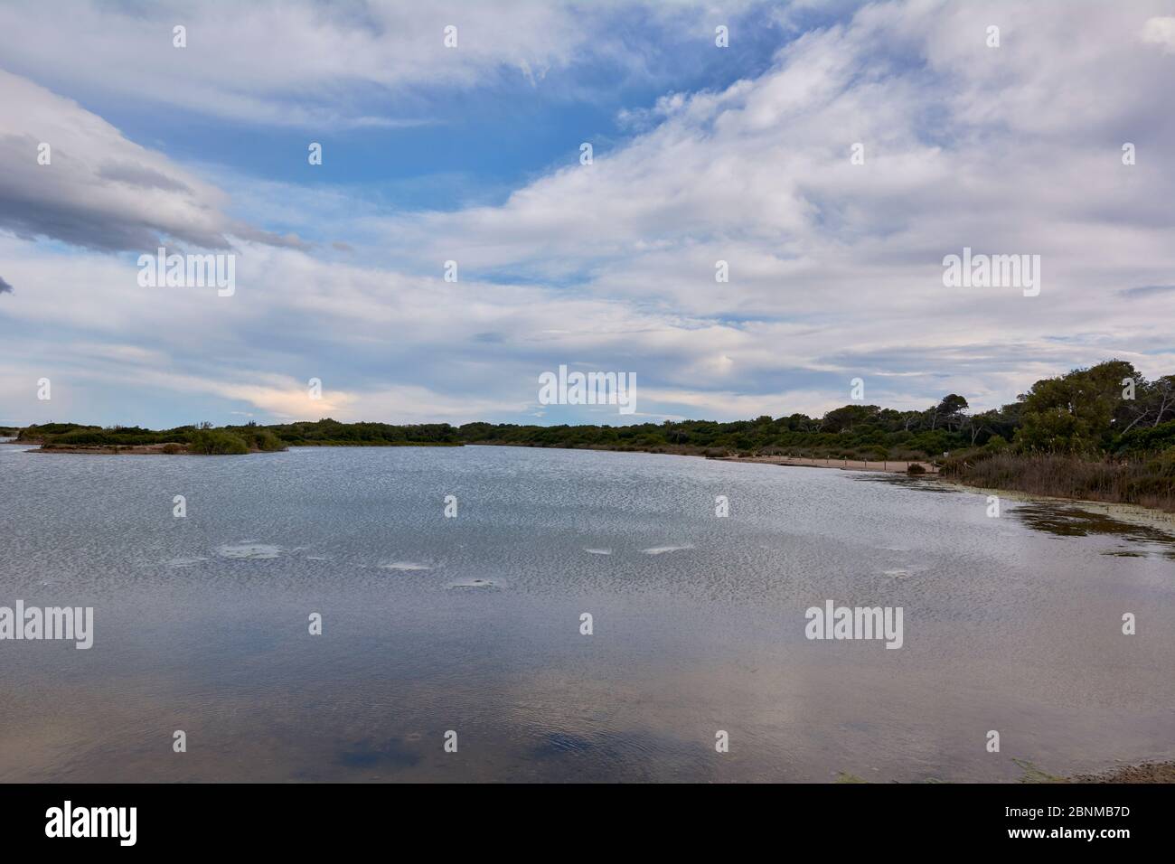 Lake with calm waters after the storm, dramatic clouds, blue sky and ...