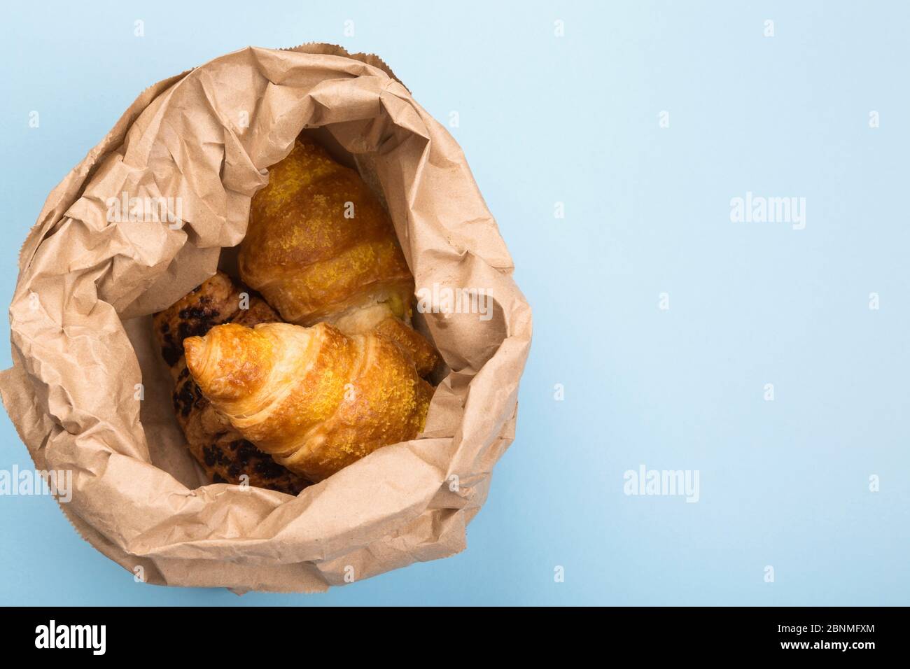 Breakfast to go - croissants in paper package on blue background ...