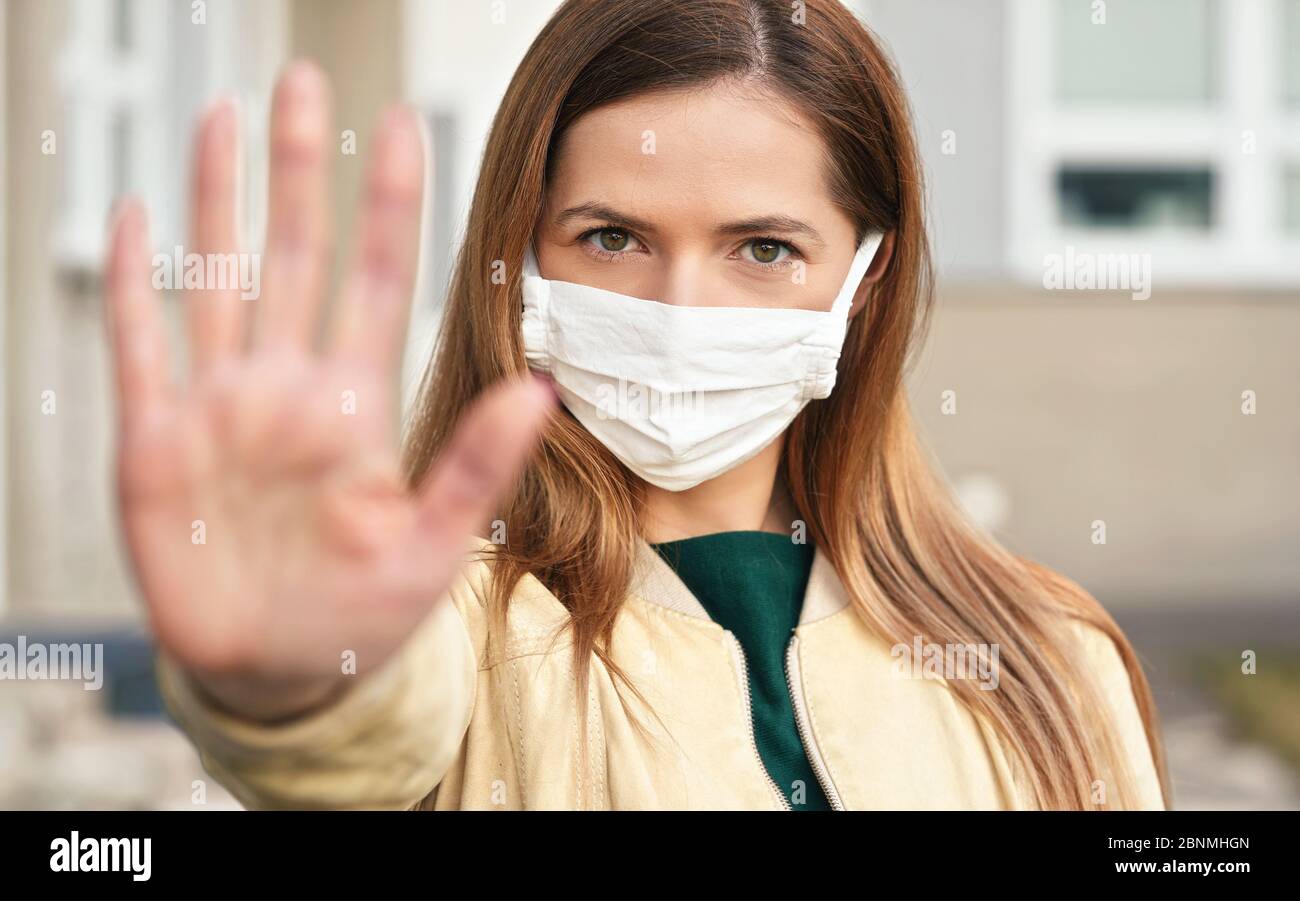 Young woman wearing white cotton virus mouth nose mask, holding hand in ...