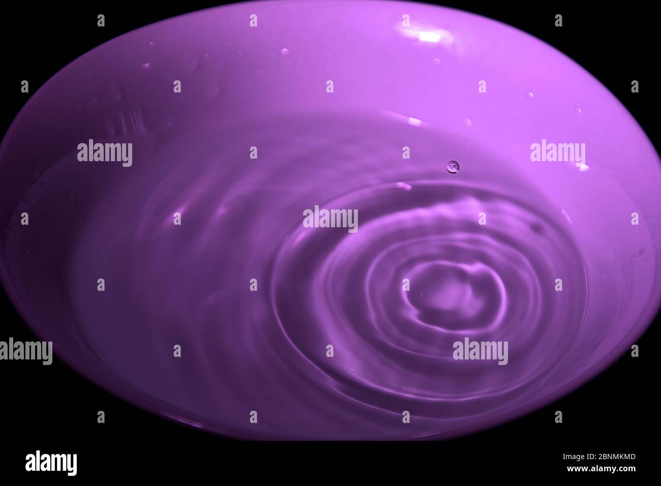 Drop of water on white bowl, Violet, black background Stock Photo - Alamy