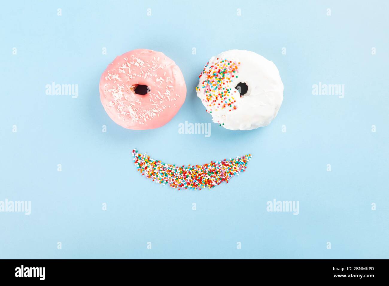 Donut with white and pink icing and multicolored sugar pastry topping ...