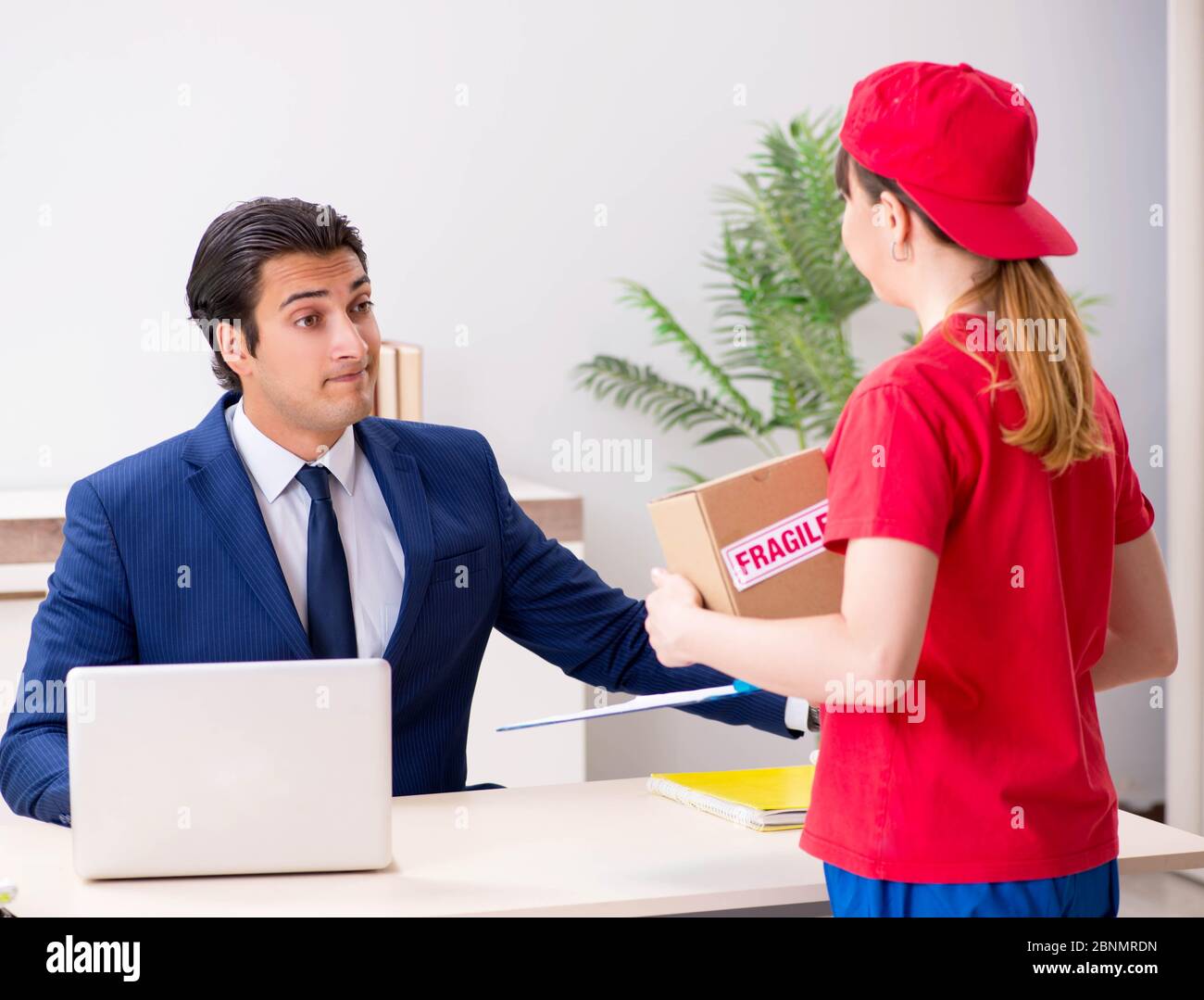The courier delivering parcel to the office Stock Photo - Alamy