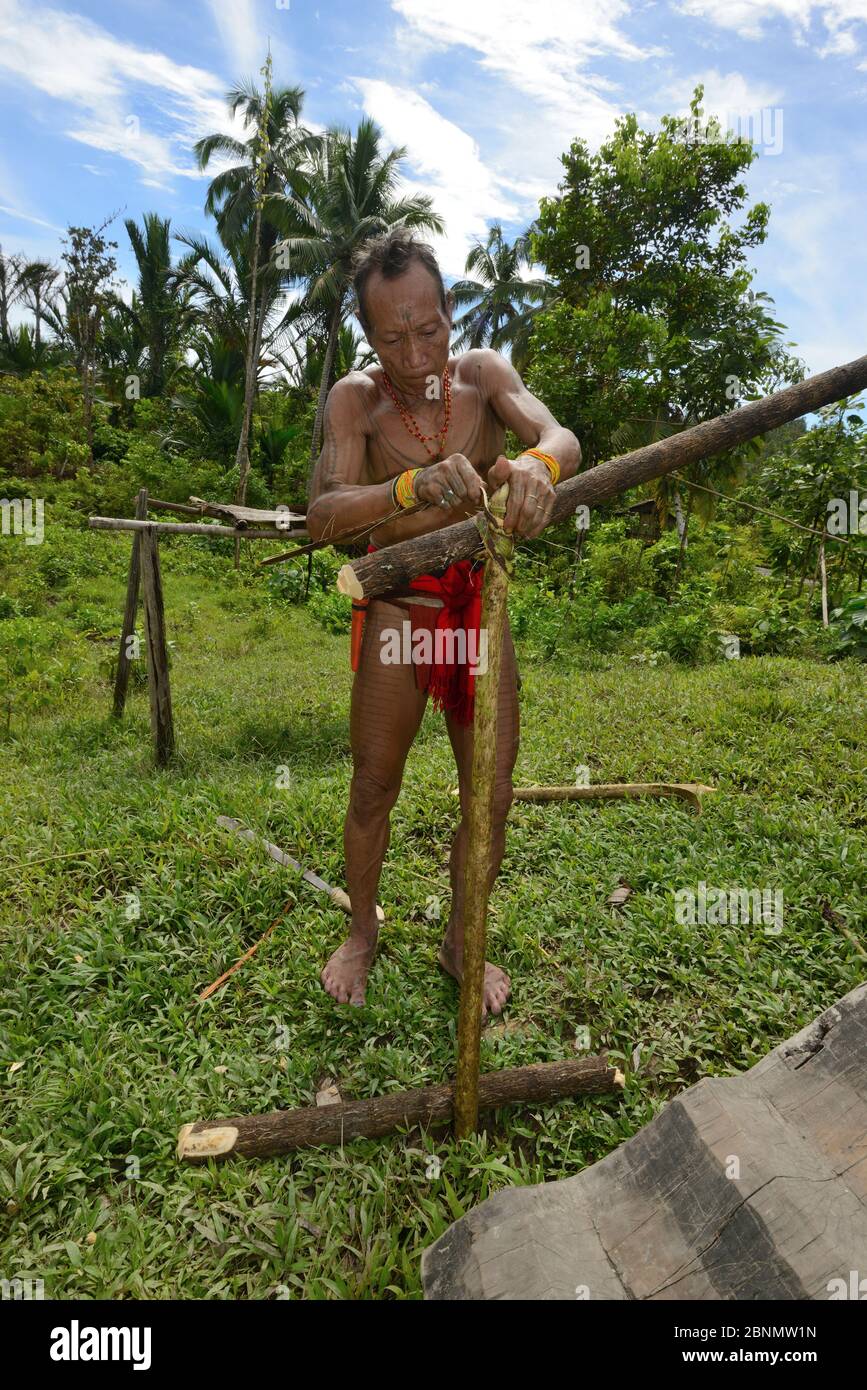 Mentawai man making a banister for steps to the uma (communal long ...