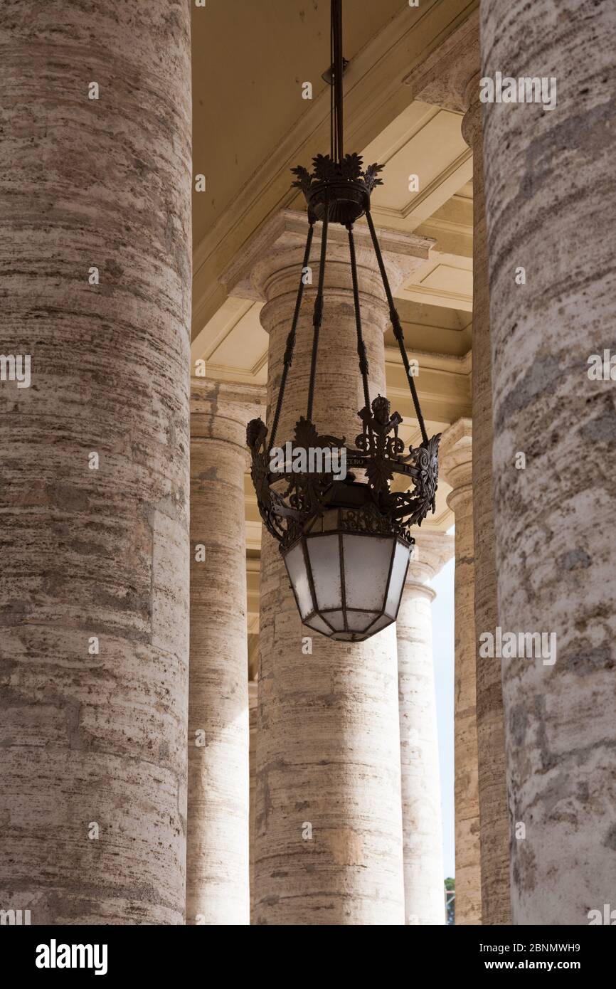 Decorative lamp among the surrounding stone columns of St Peters square ...