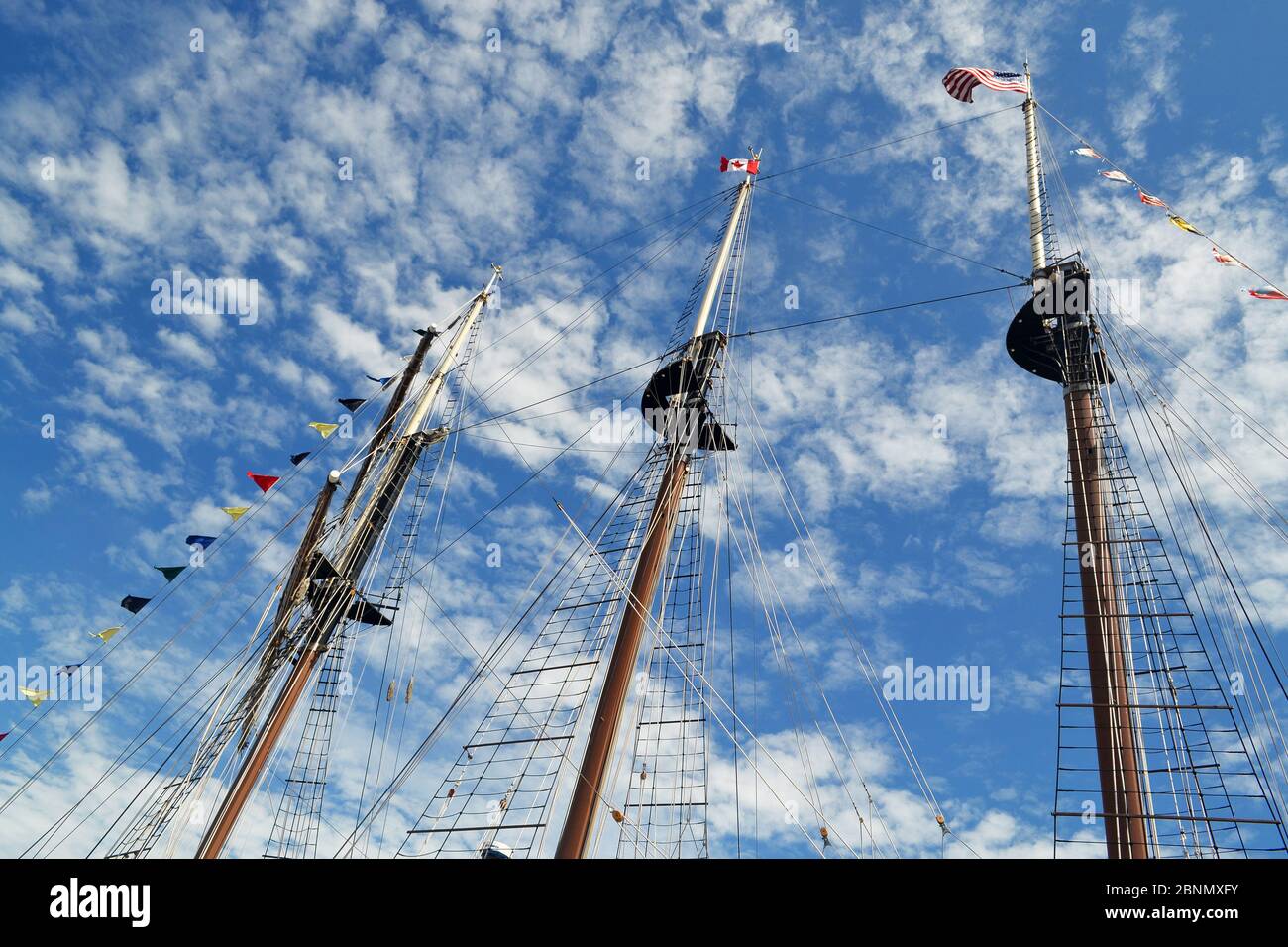 The tree masts of a large tall ship with there flags under a sonny sky ...