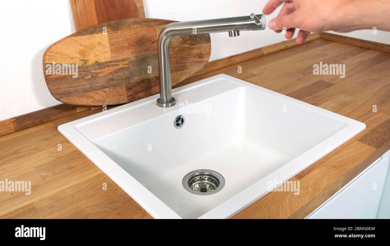 Hand opening water tap with white washing sink in kitchen Stock Photo ...