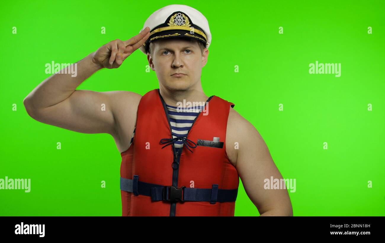 Young muscular sailor man works as lifeguard at beach salutes with hand ...