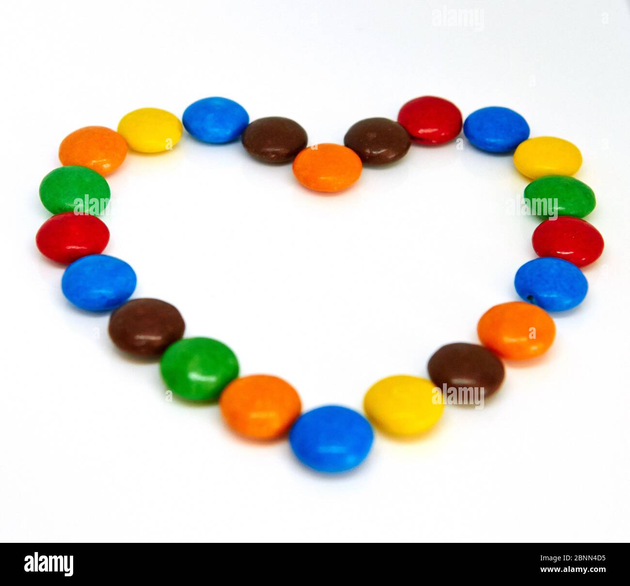 Colorful chocolate buttons in the shape of heart on a white background ...