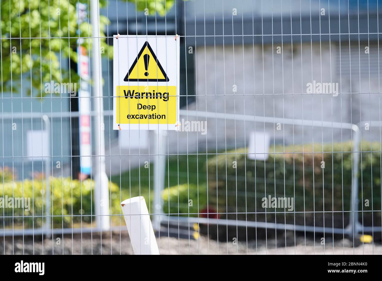 Deep excavations danger sign on fence with trench hole in background on ...