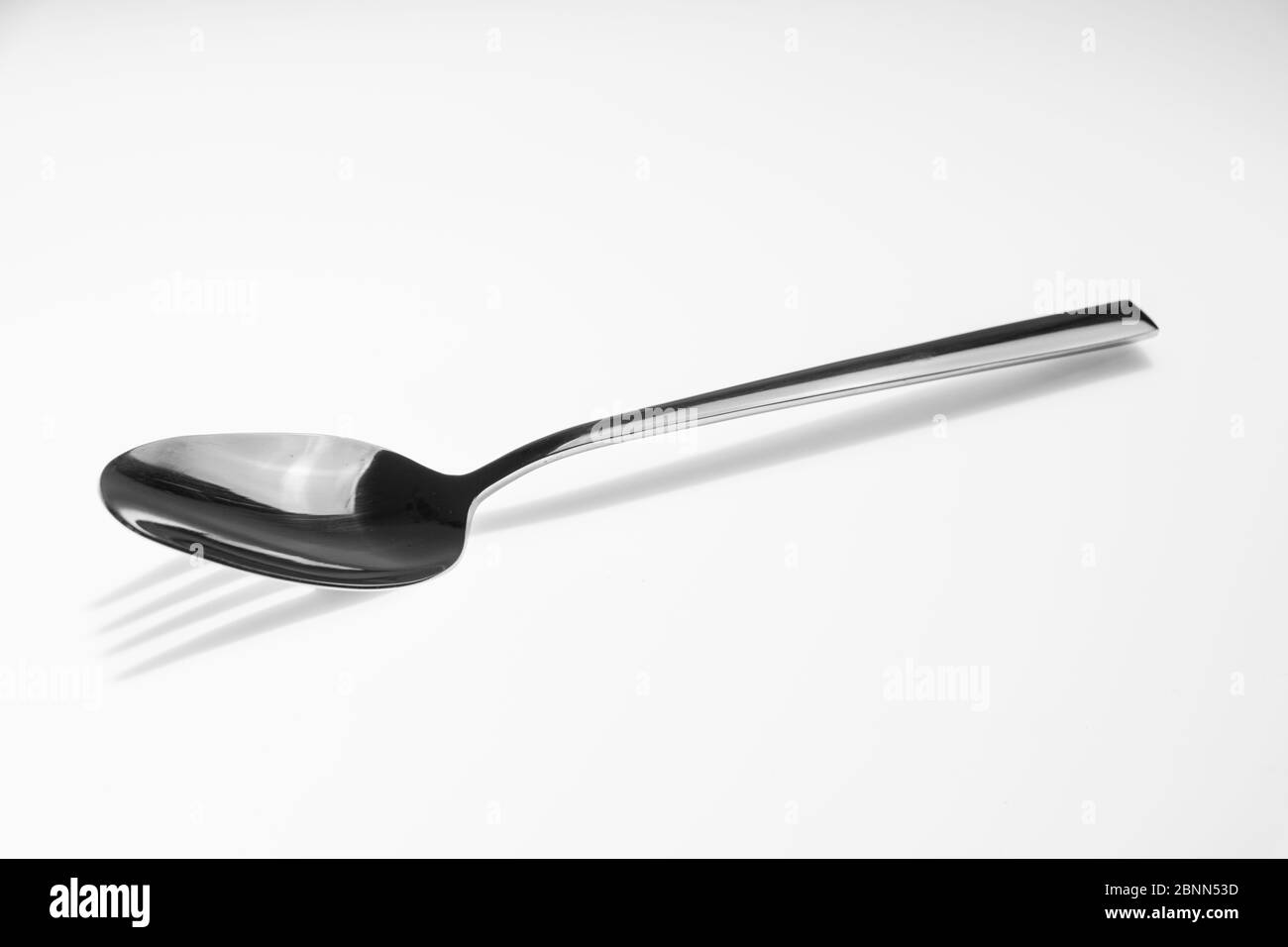Metal spoon casting a fork shadow on white background Stock Photo - Alamy