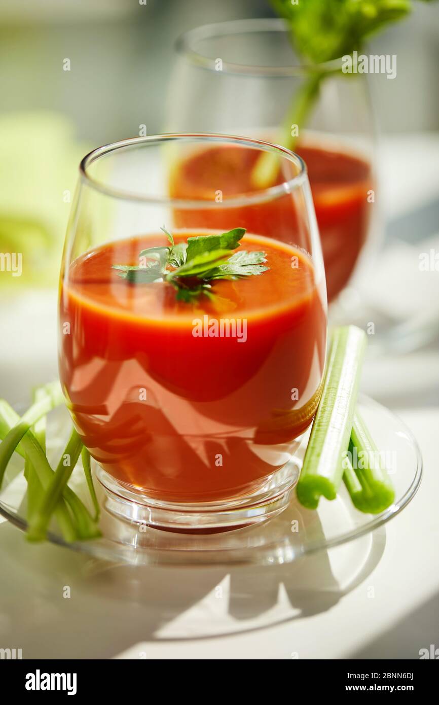 Tomato juice on a white plate with a garnish of celery and parsley. Healthy eating concept Stock ...