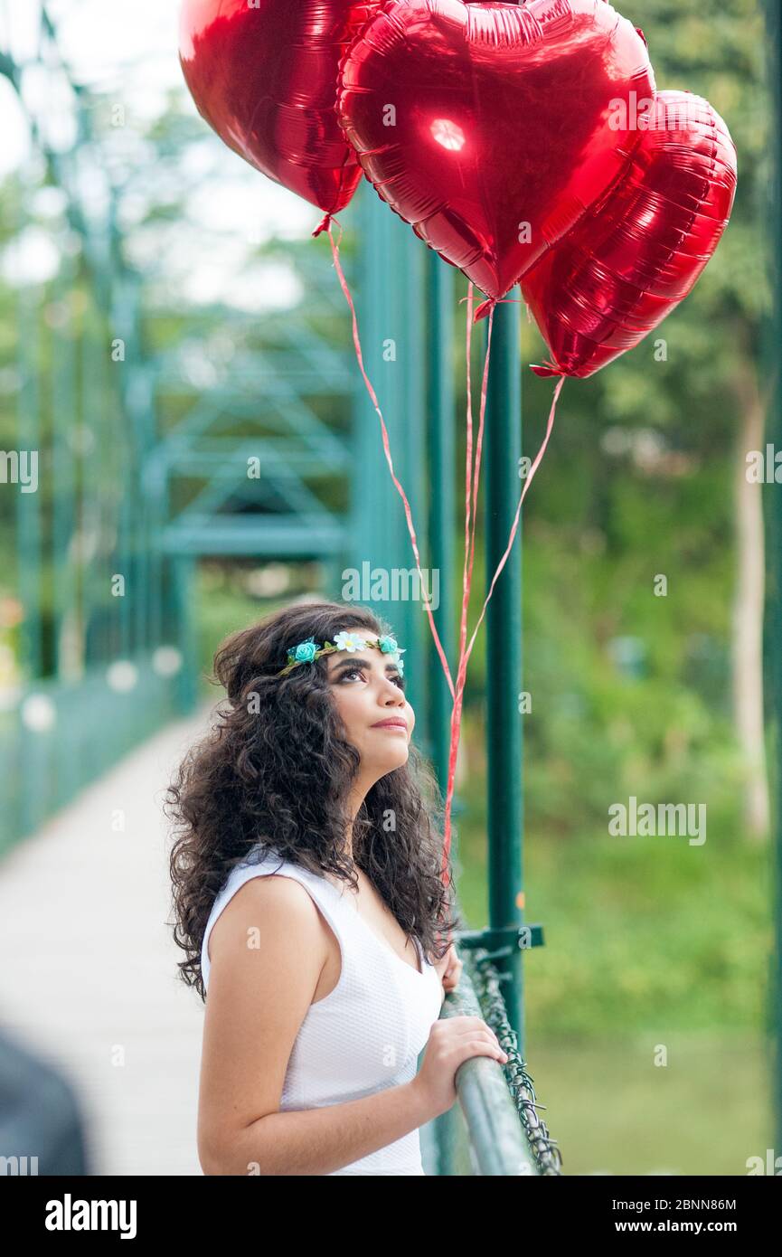 Pretty girl looking up holding red balloons in heart shape Stock Photo ...